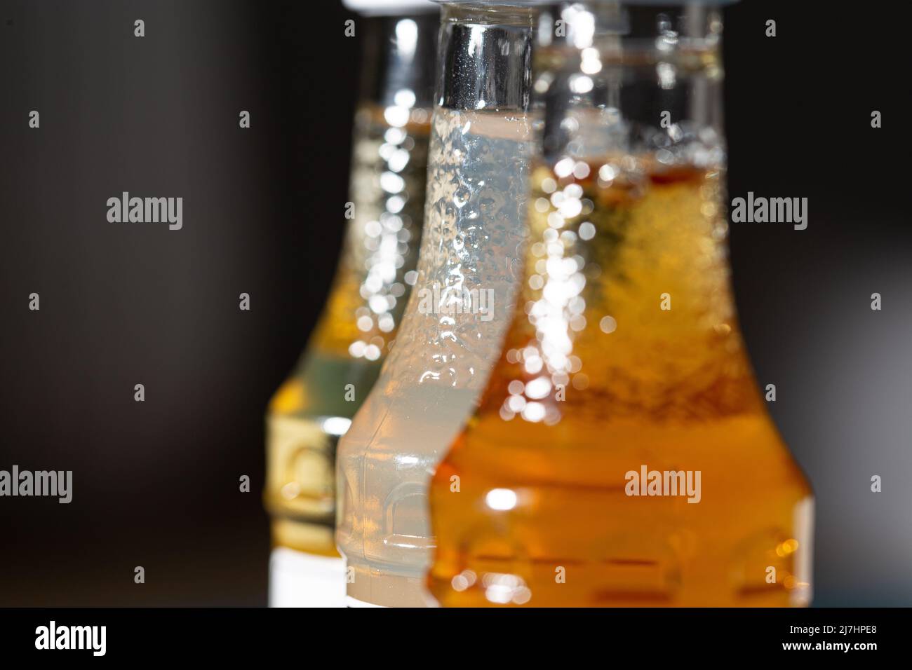 Different alcoholic liquor drink bottles in a row with textured glass ...