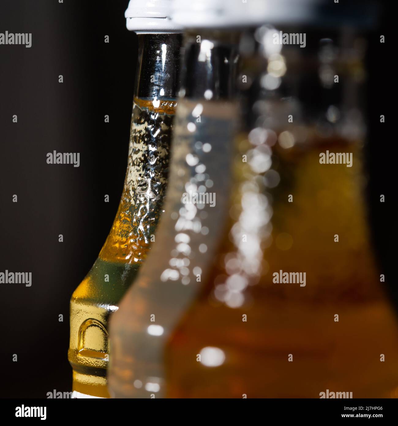 Different alcoholic liquor drink bottles in a row with textured glass ...