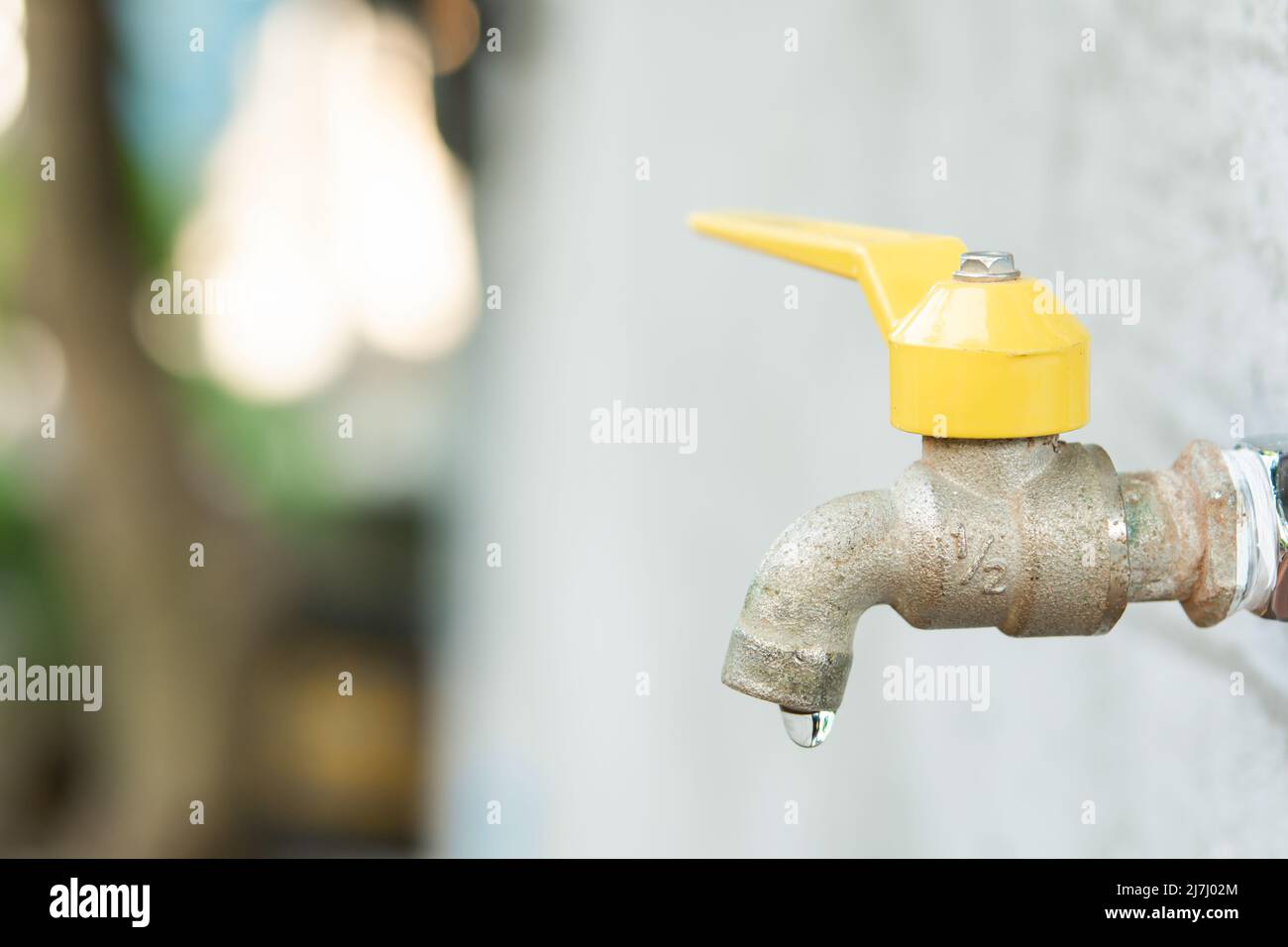 Faucet with a water drop. Old yellow faucet Stock Photo - Alamy