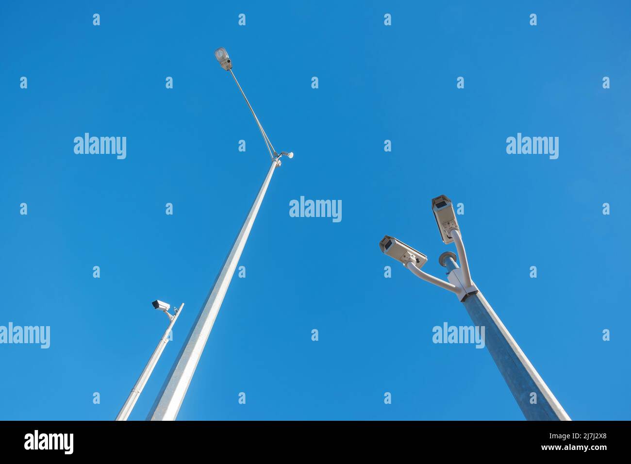 Looking up at three CCTV surveillance cameras and streetlight against a ...