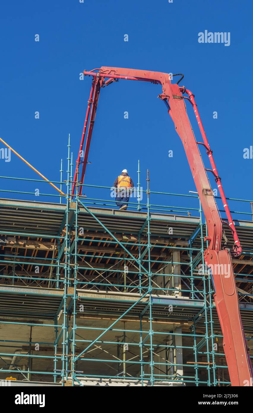 A construction site with scaffolding, a worker wearing high visibility ...