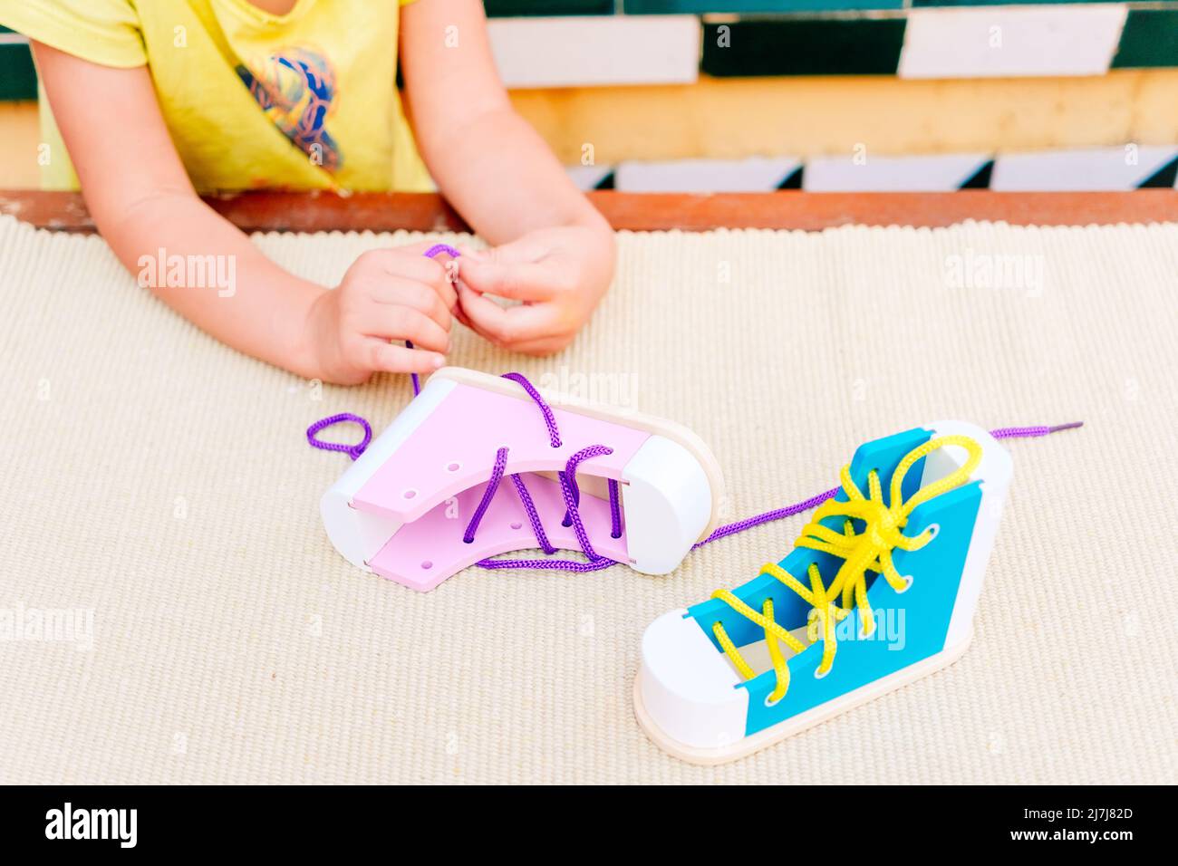 Girl uses montessori educational material to learn how to tie shoelaces ...