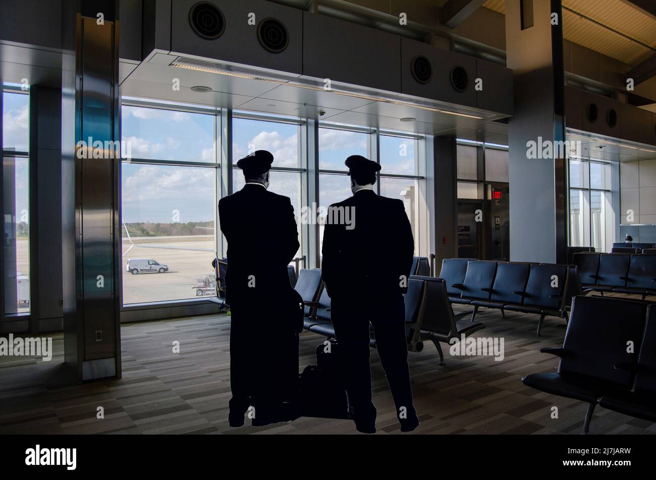 Empty Airport waiting area with the silhouette of two airline pilot ...
