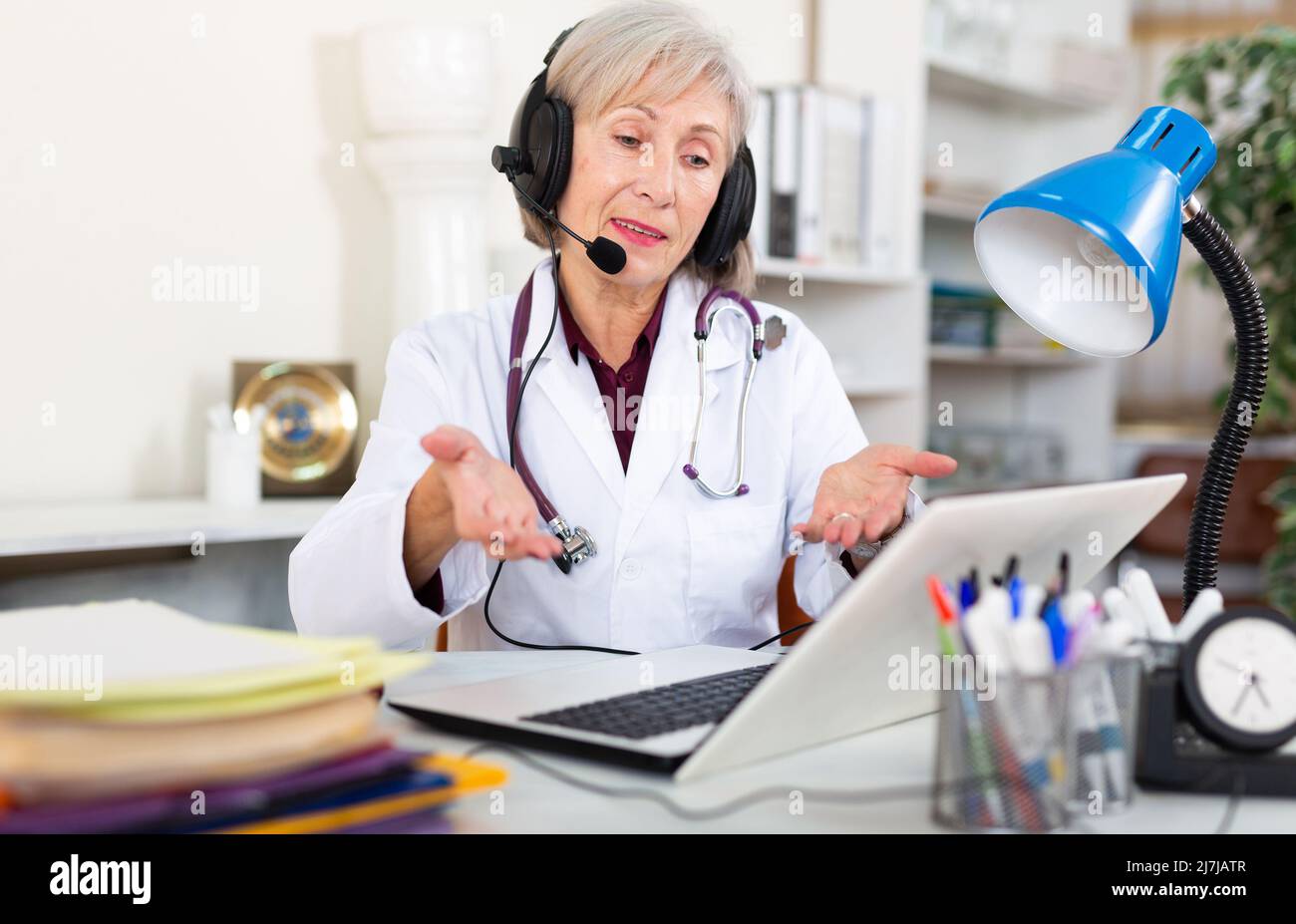 Female doctor in headphones with microphone consults patient on ...