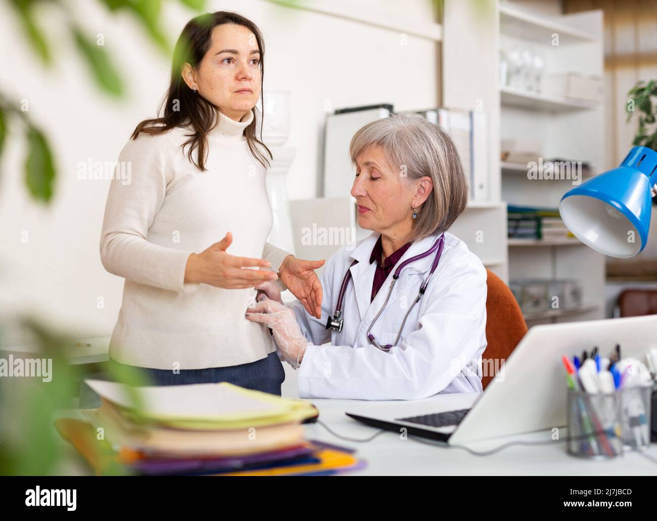 Aged female doctor palpating abdomen of woman suffering from pain Stock ...