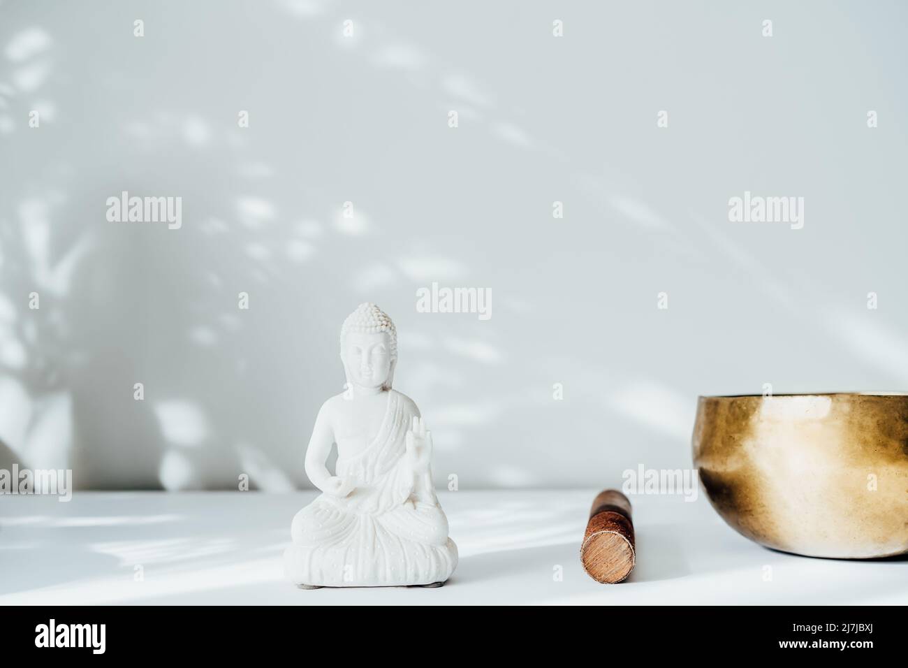 Decorative white Buddha statuette and tibetian singing bowl on the ...