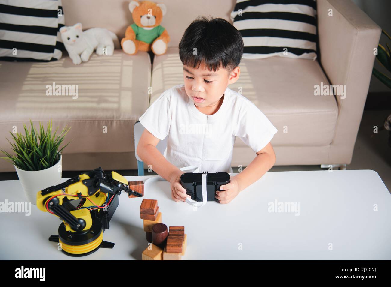 Happy Asian little kid boy using remote control playing robotic machine ...