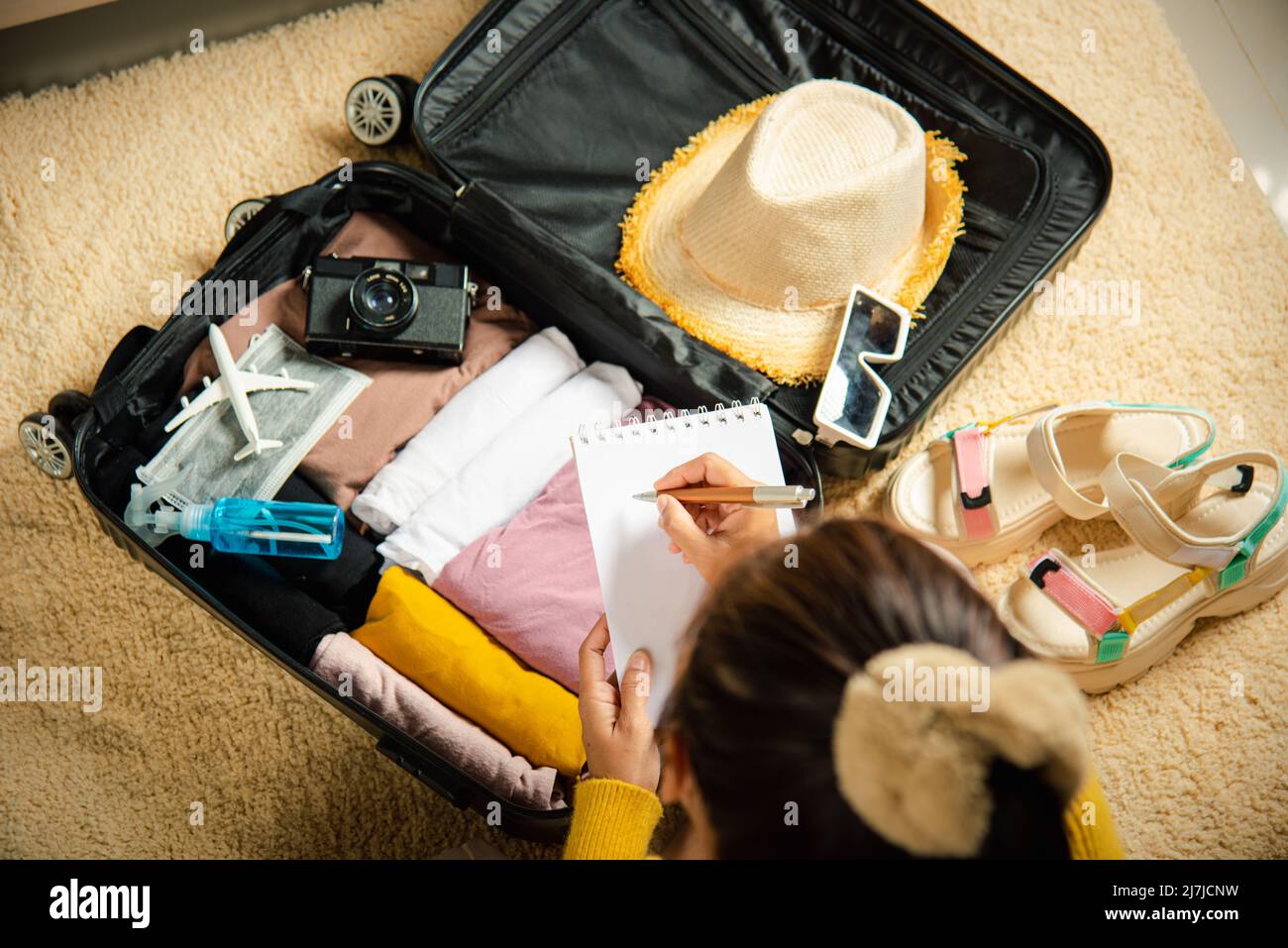 Making check list of things to pack for travel. Woman writing paper ...