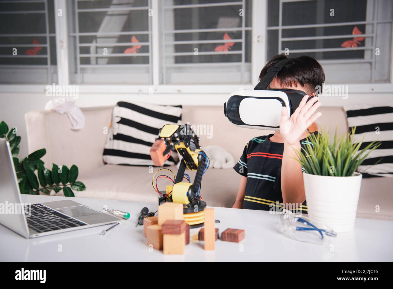 Asian kid boy using VR glasses on robotic arm in workshop, Child ...