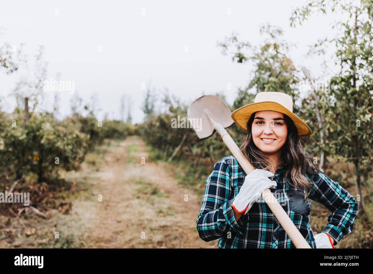 Young smiling latin peasant woman with a shovel on her shoulder. Role ...