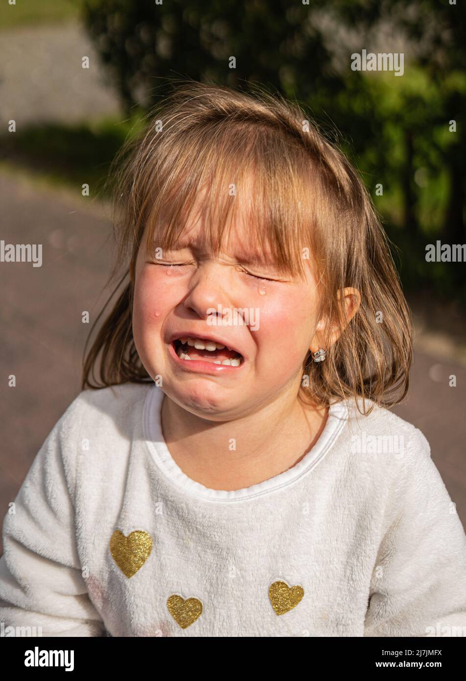 Caucasian kid girl crying alone outside Stock Photo - Alamy