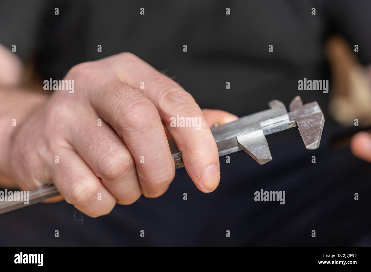 A man's hand holding a caliper. An adult man with a high-precision ...