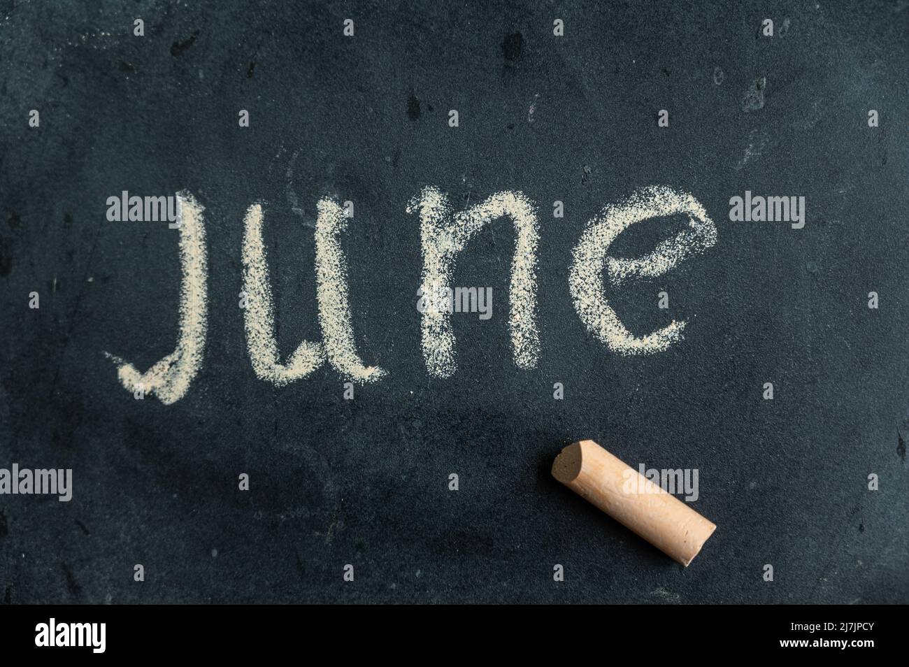 June. Name of the first summer month written in yellow chalk on a black ...