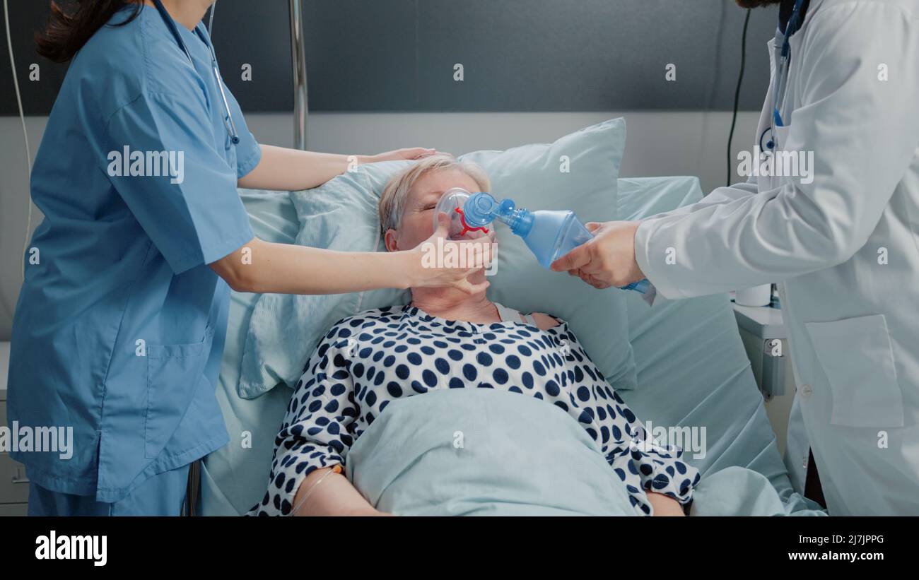 Doctor and nurse using oxygen tube for hyperventilating woman in bed ...