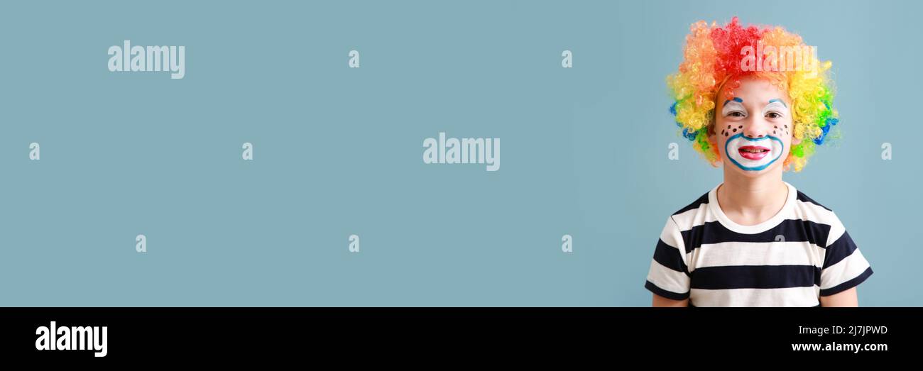 Cute little boy in clown disguise on color background with space for ...