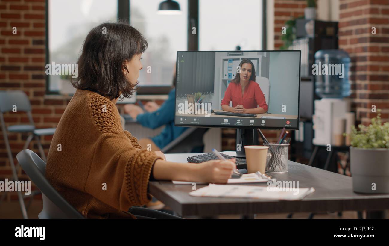 Employee waving at video call camera to talk to manager on computer ...