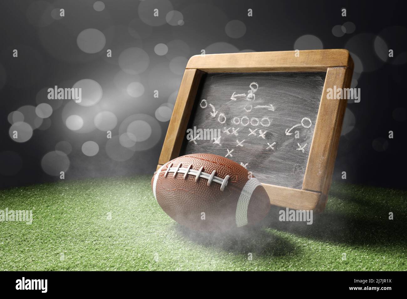 Rugby ball and chalkboard with scheme of game on green grass against ...