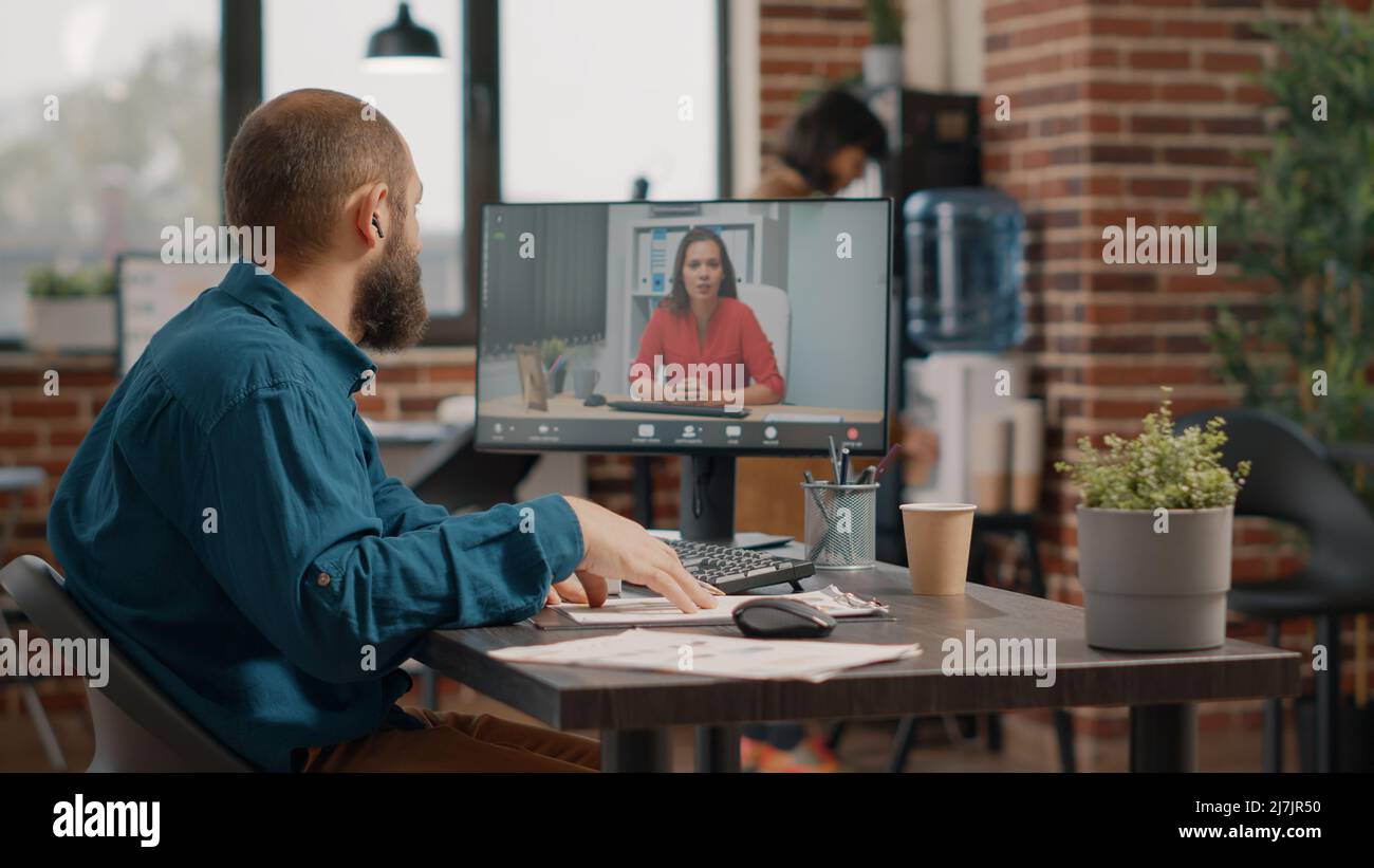 Business man using video call to talk to woman on computer in startup ...