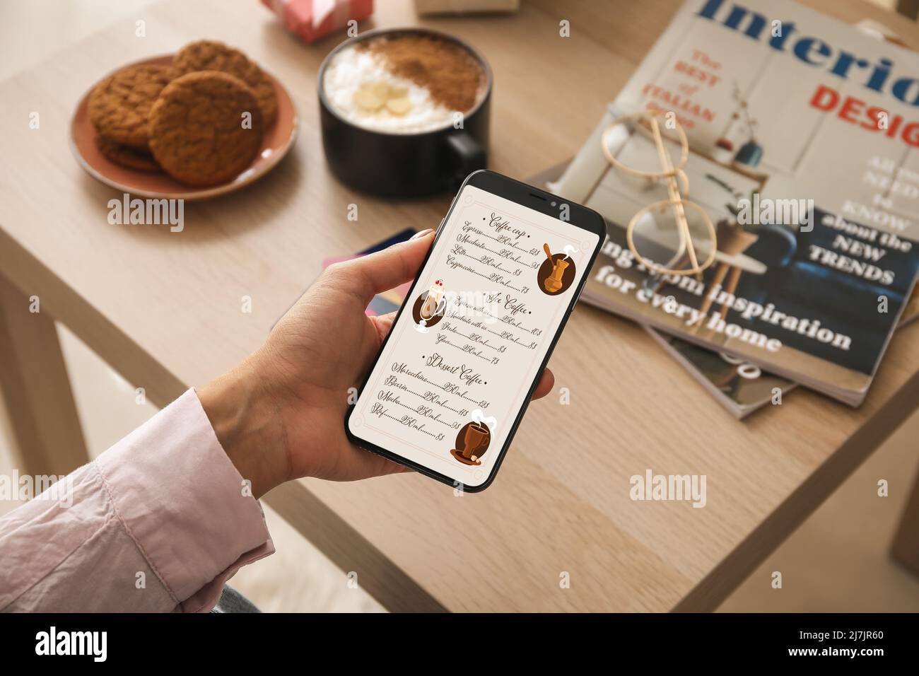 Young woman reading menu on screen of mobile phone before ordering food ...