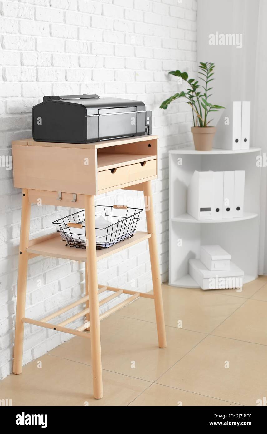 Interior of modern room with standing desk and printer near white brick ...