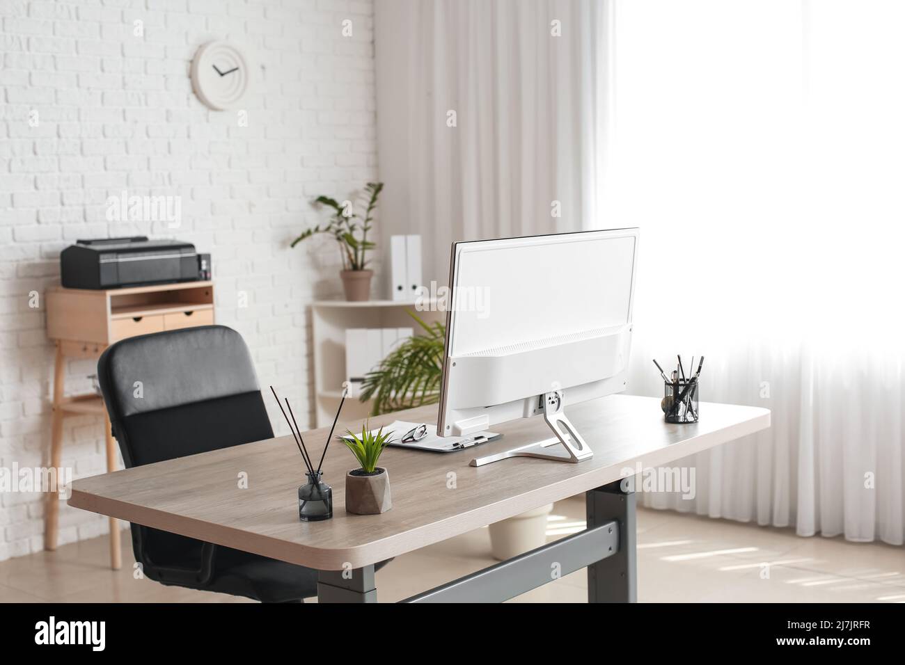 Comfortable workplace with modern computer, reed diffuser and ...