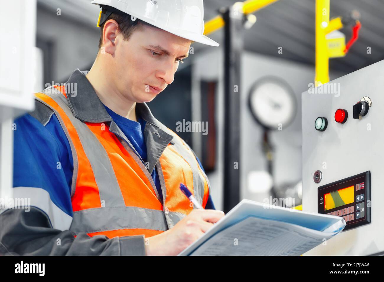 Young engineer in helmet and vest stands inside compression station and ...