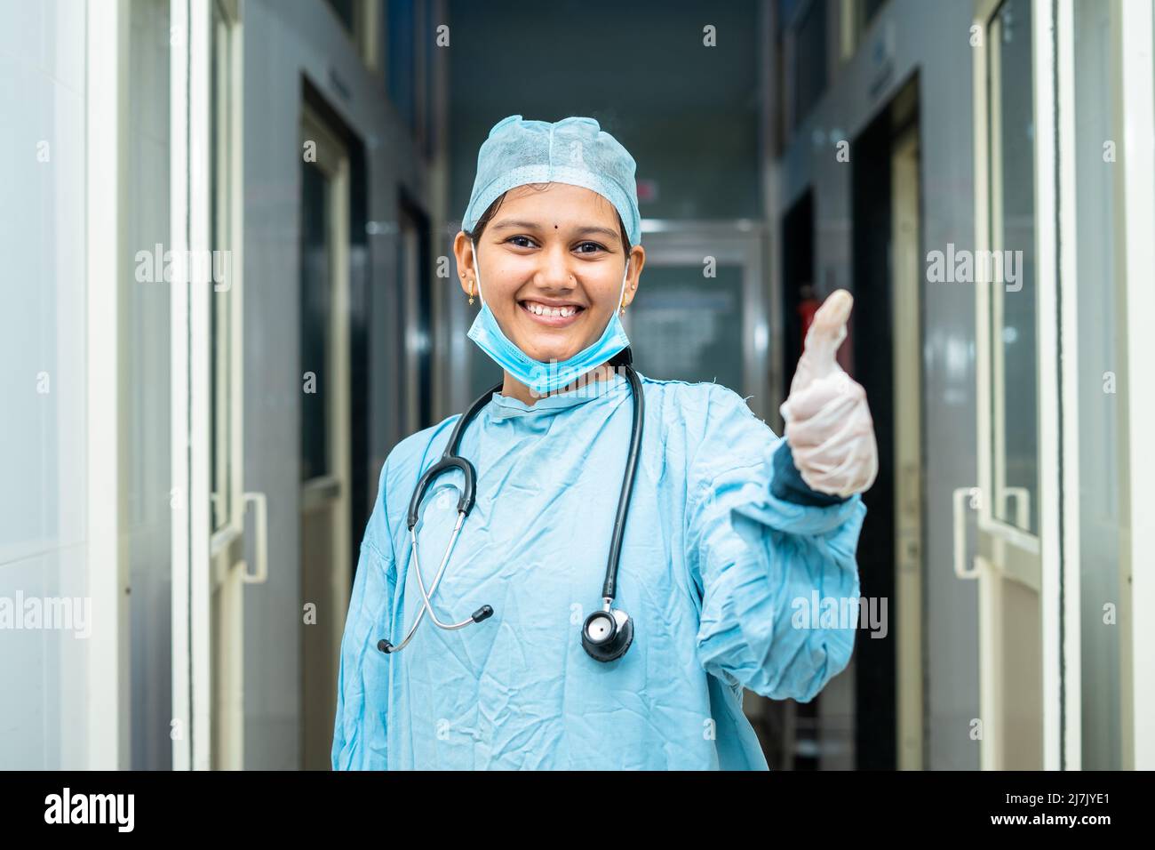 Happy young surgeons in operation gown showing thumbs up by looking at ...