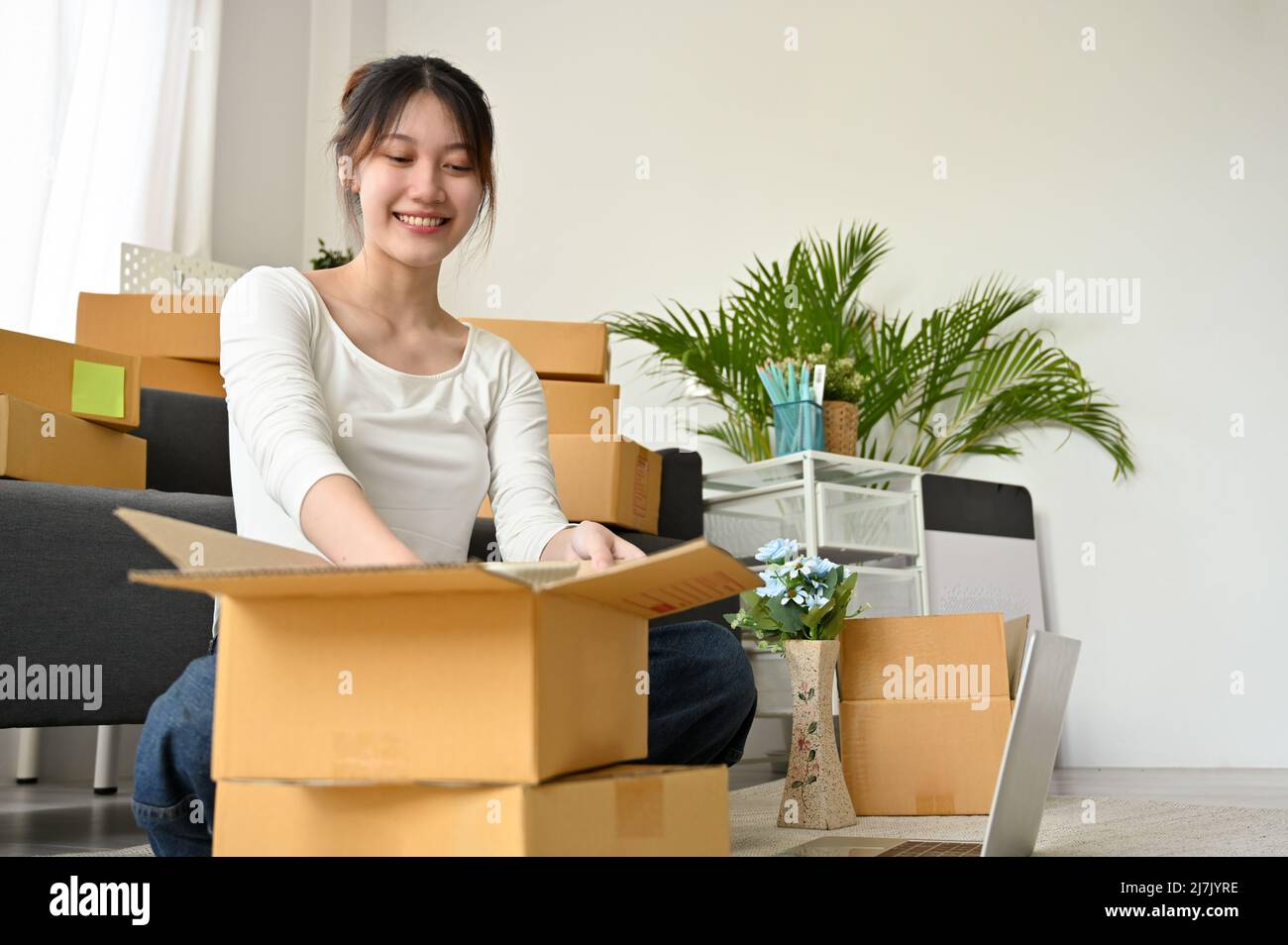 Attractive Asian young woman packing her stuff in a cardboard boxes ...