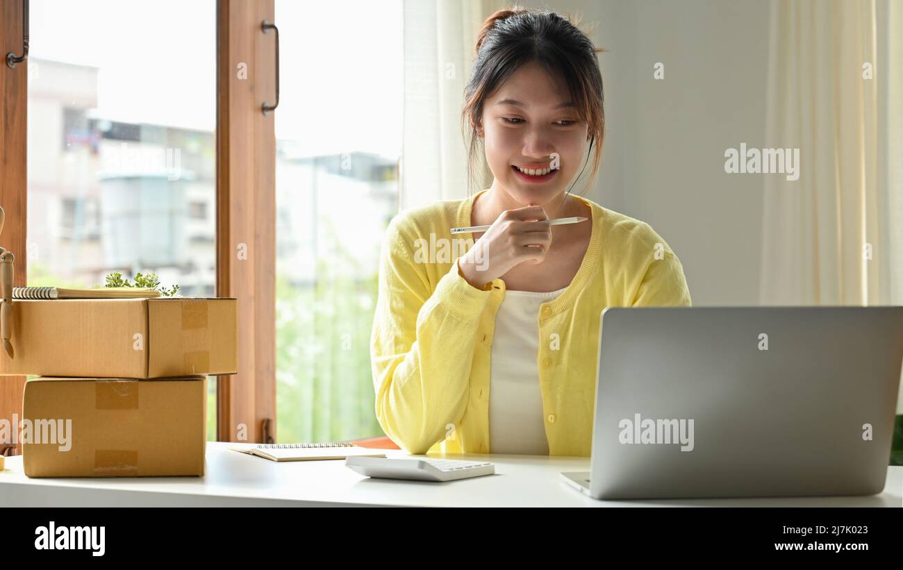 Smart and successful Asian young online seller using laptop computer ...