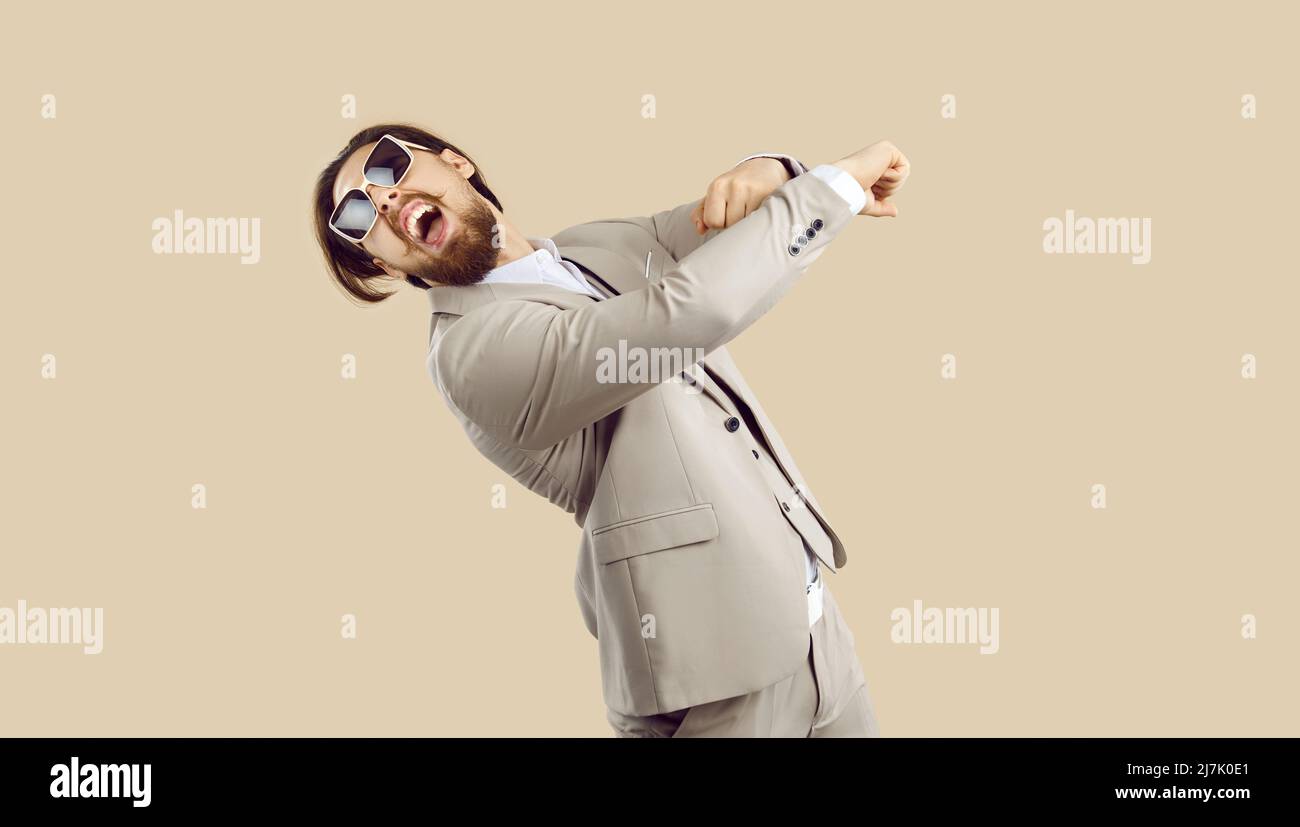 Funny crazy man in elegant suit and cool sunglasses dancing on beige ...