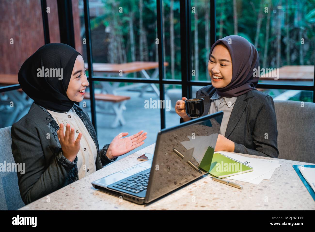 asian muslim woman talking while enjoying coffee and working Stock ...