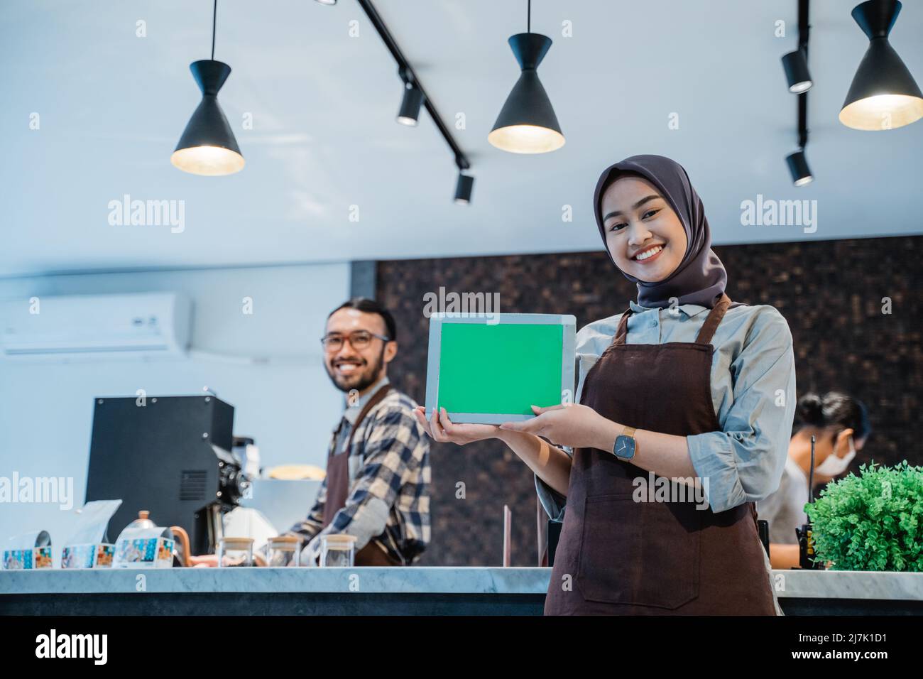 muslim cafe worker holding blank screen tablet promotion and smiling ...