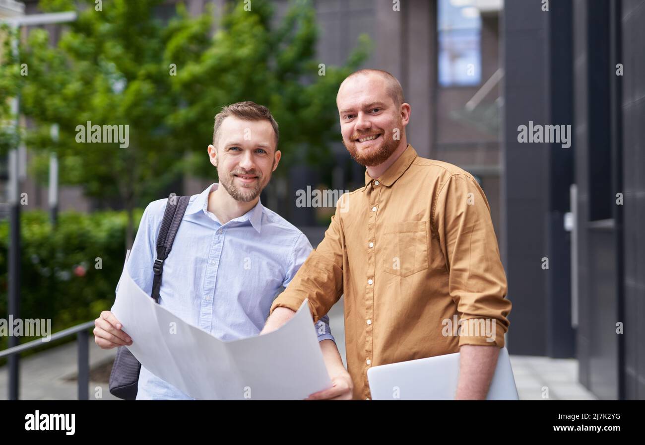 Confident team of architect or designer managers holding drawings or ...