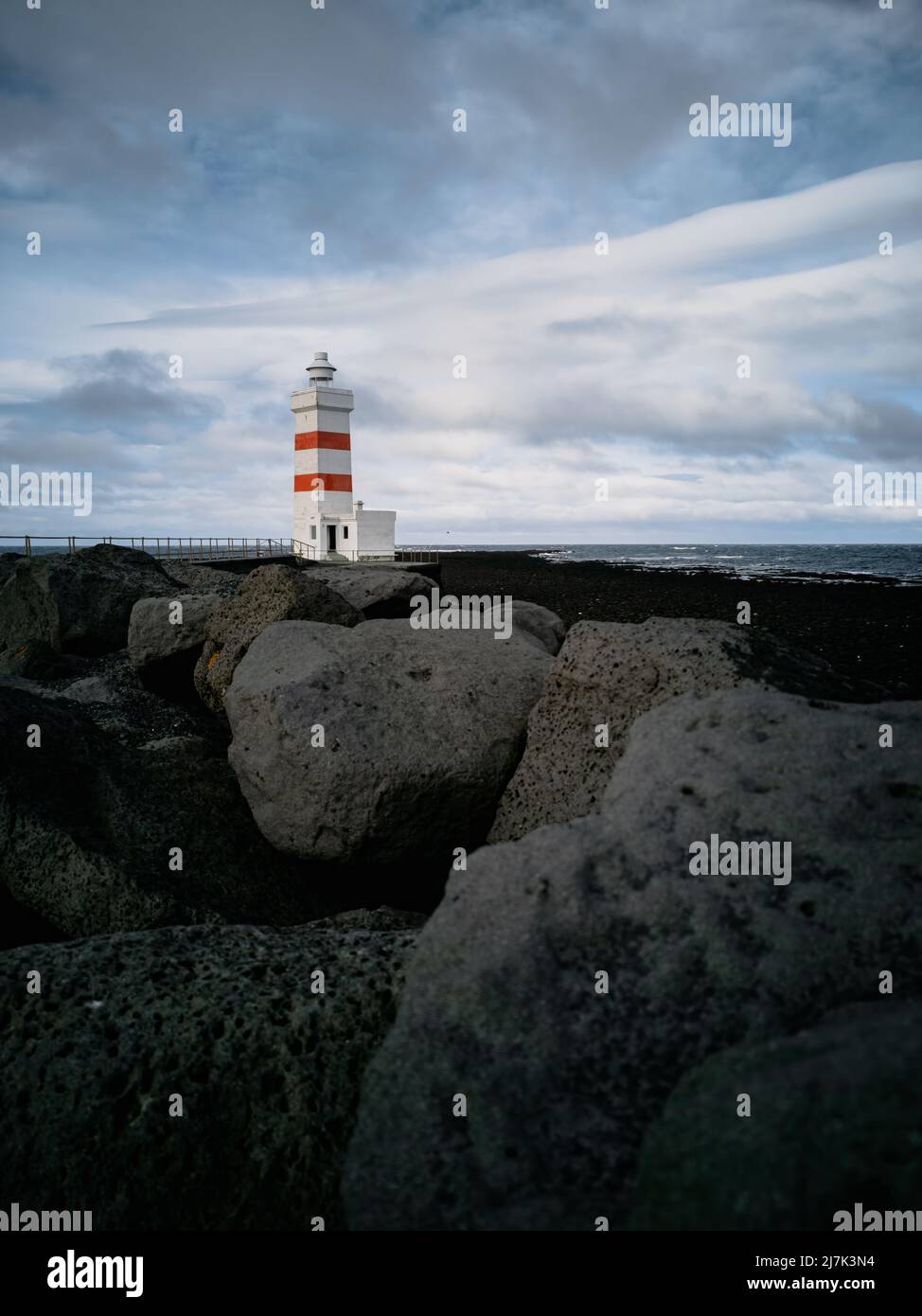 Lighthouse with red stripes wide angle over the black rocks Stock Photo ...