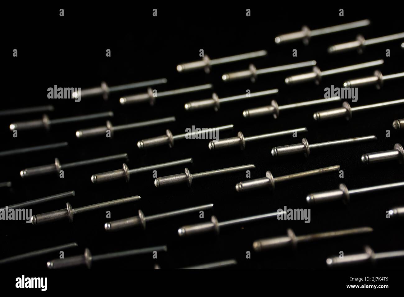 rivet nails arranged in lines on black background Stock Photo - Alamy