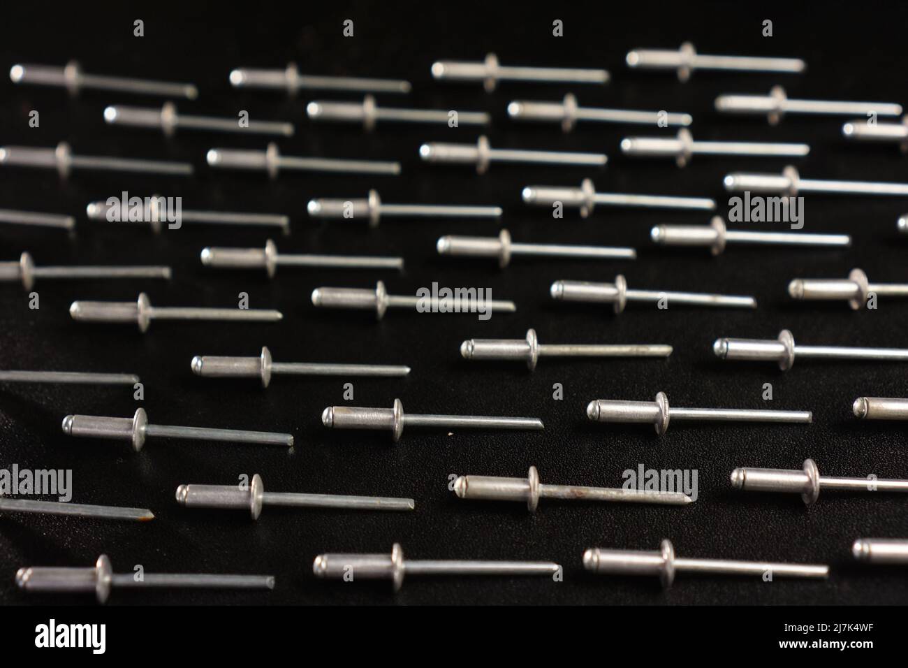 rivet nails arranged in lines on black background Stock Photo - Alamy