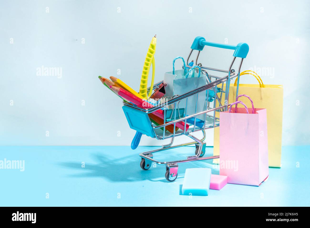 School sale concept. Shopping supermarket cart with colorful paper bags ...