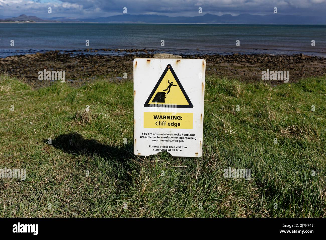 Yellow and white Danger cliff edge warning sign on wales coast path ...