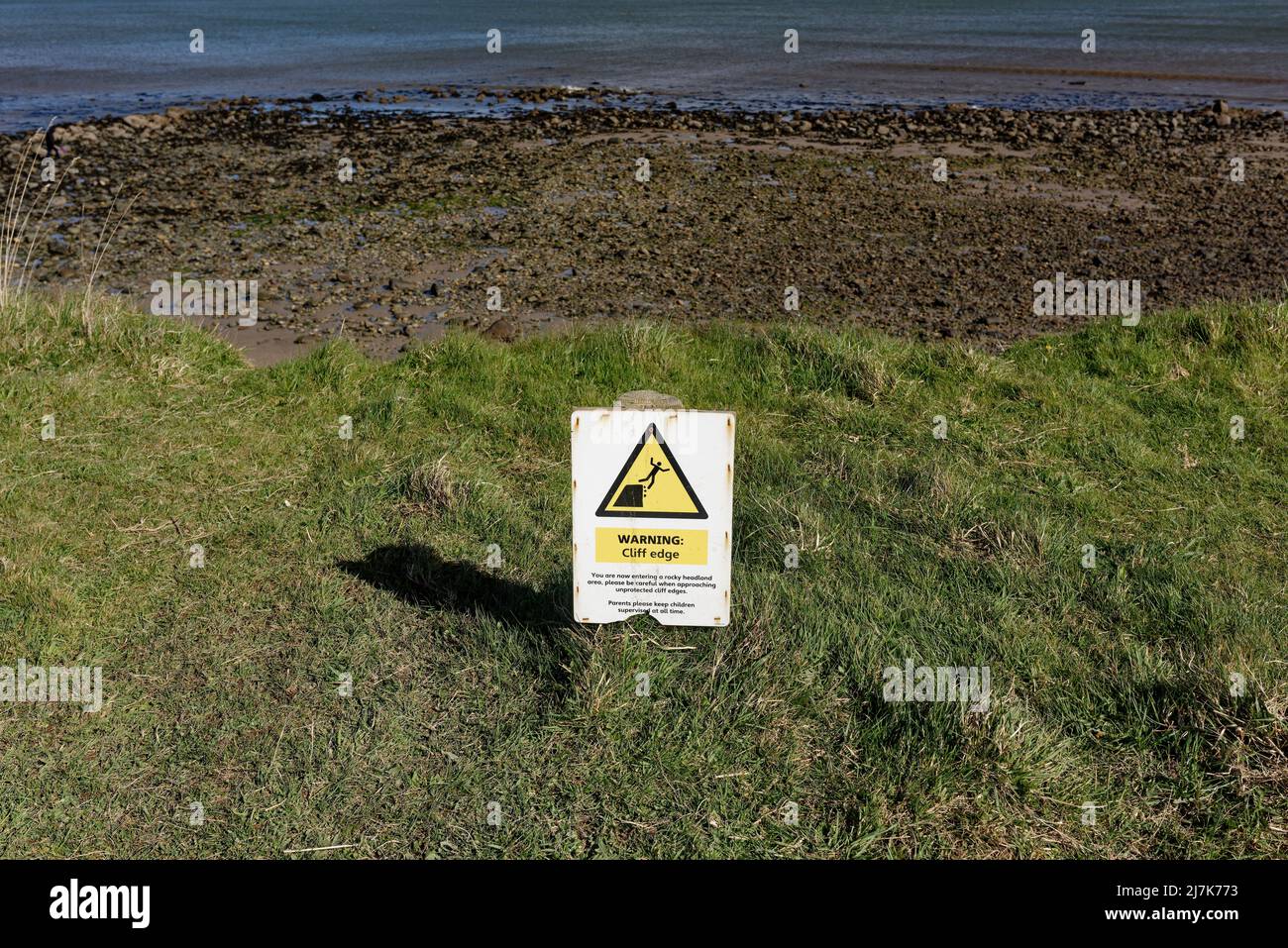 Yellow and white Danger cliff edge warning sign on wales coast path ...