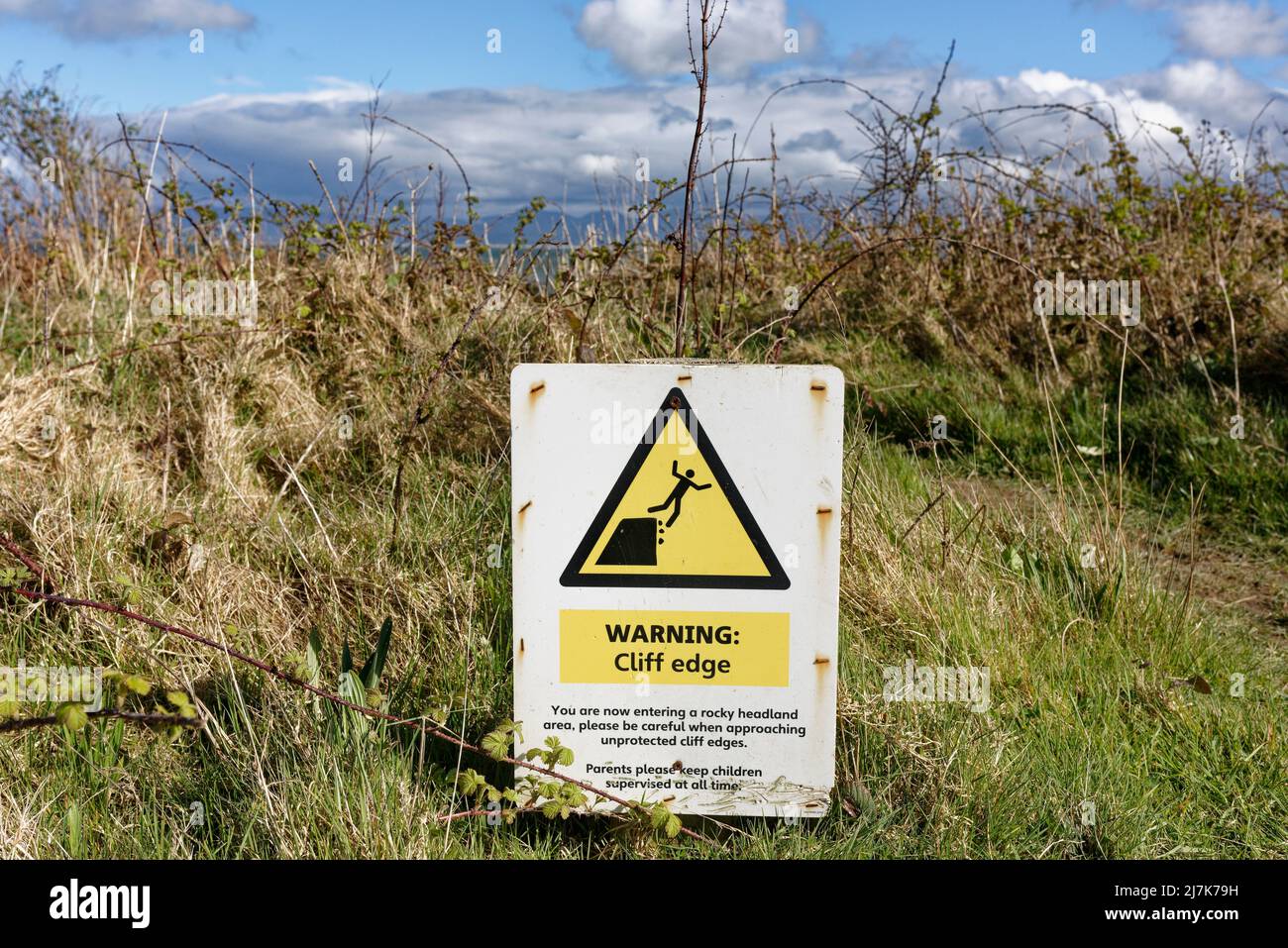 Yellow and white Danger cliff edge warning sign on wales coast path ...