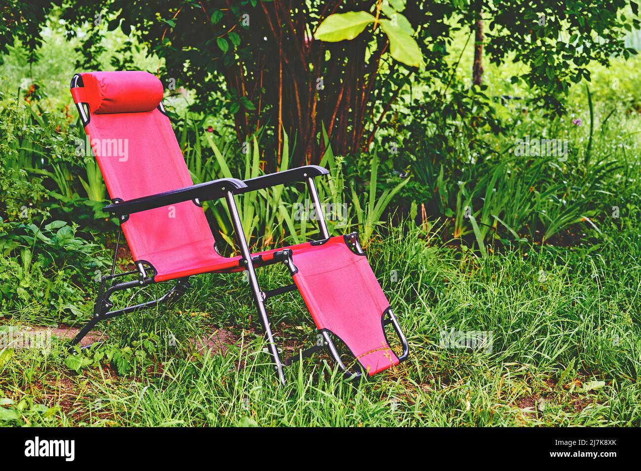 Red chaise lounge chair on summer green meadow Stock Photo - Alamy