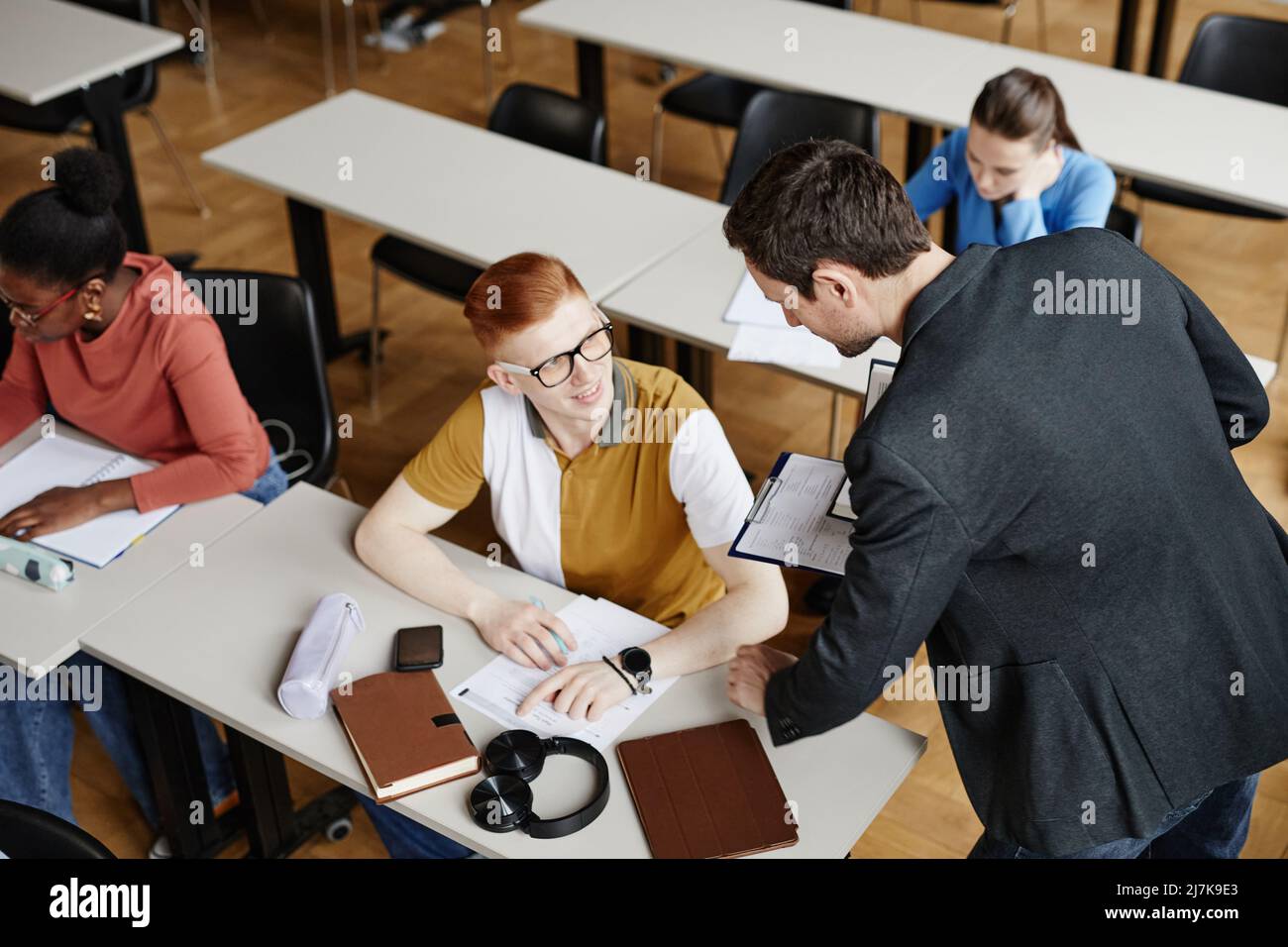 High angle portrait of male professor helping students in college ...