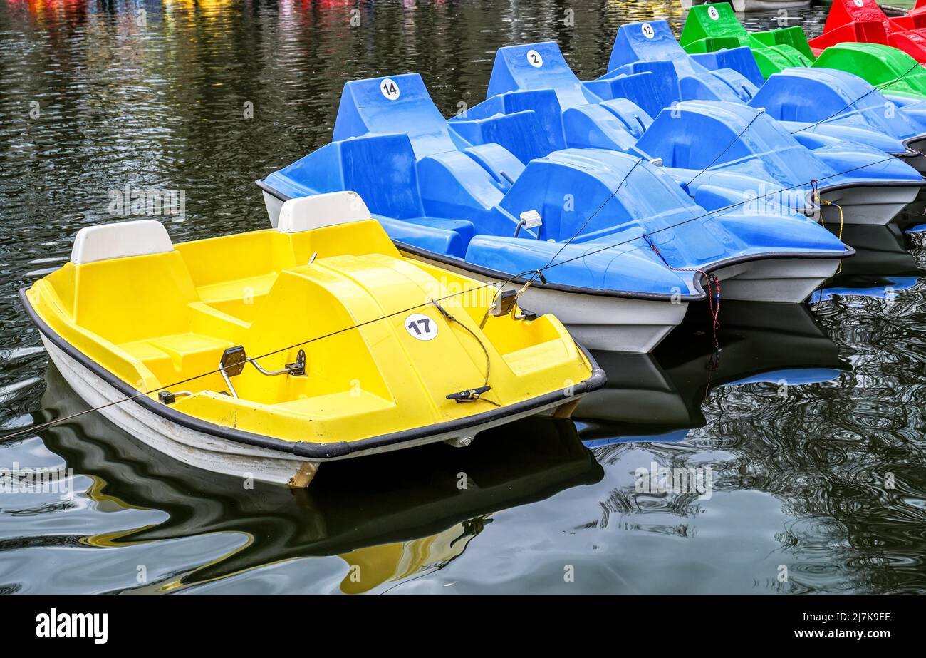 Some colorful plastic catamarans are in a row on the water surface of ...