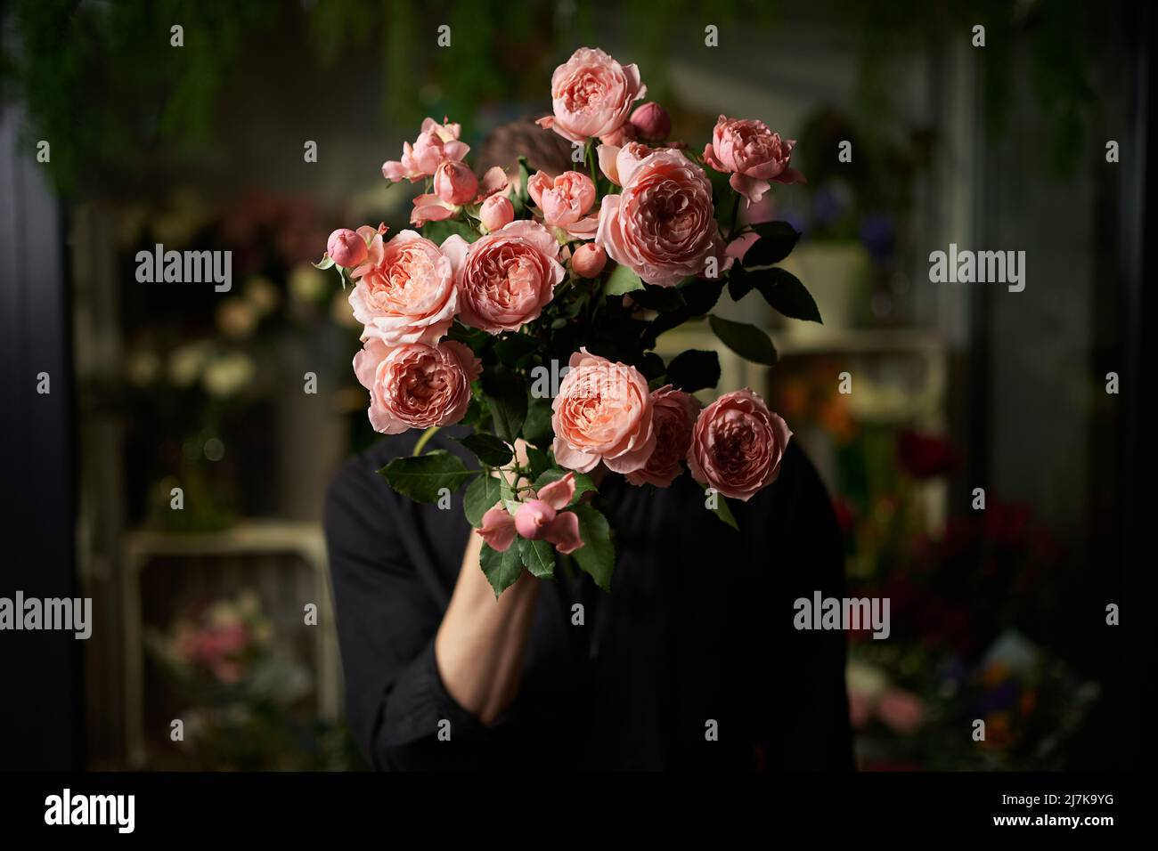 Cute male holding a bunch of fresh pink long stemmed roses in front of ...