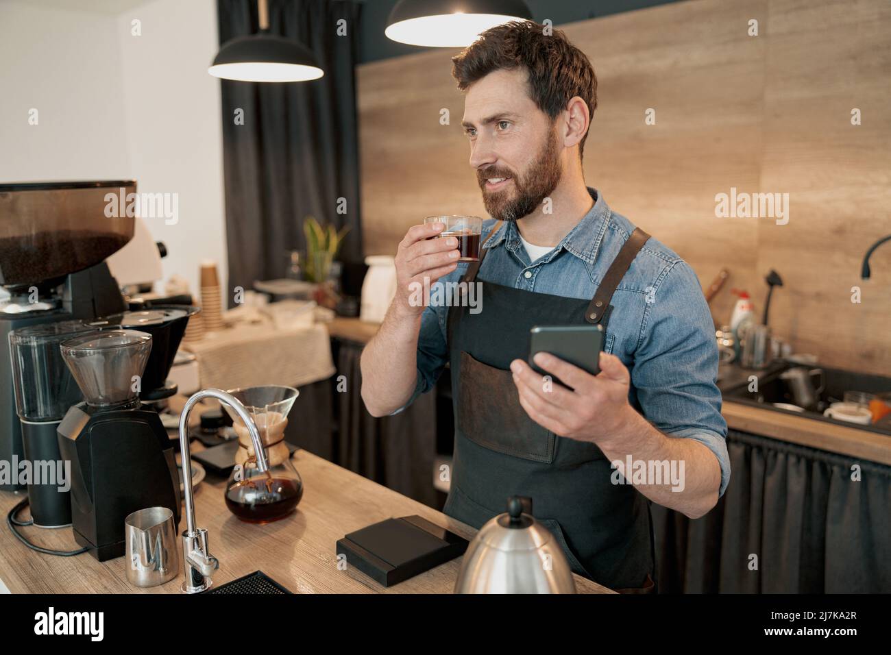 barista drinking coffee and holding phone during lunch break Stock ...