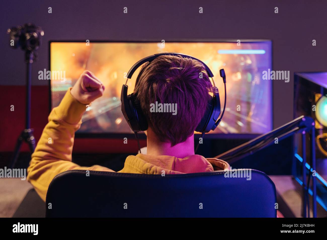 Back view of professional gamer sitting in gaming chair and celebrating ...