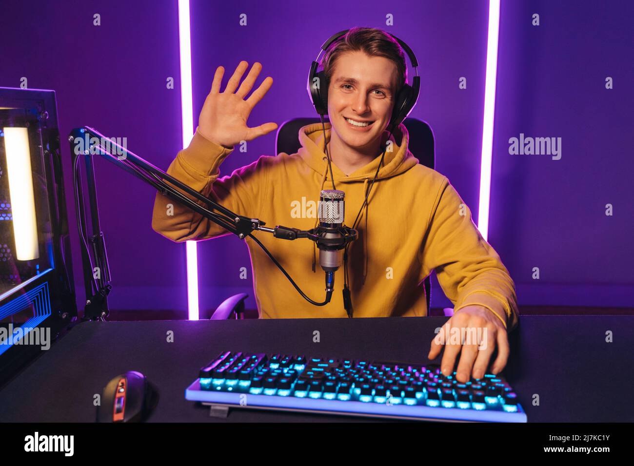 Young handsome vlogger pro gamer waving hand to camera, says hello to ...