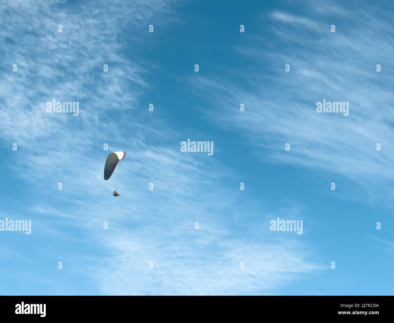 Flying paraglider on a background of bright blue sky with soft clouds ...