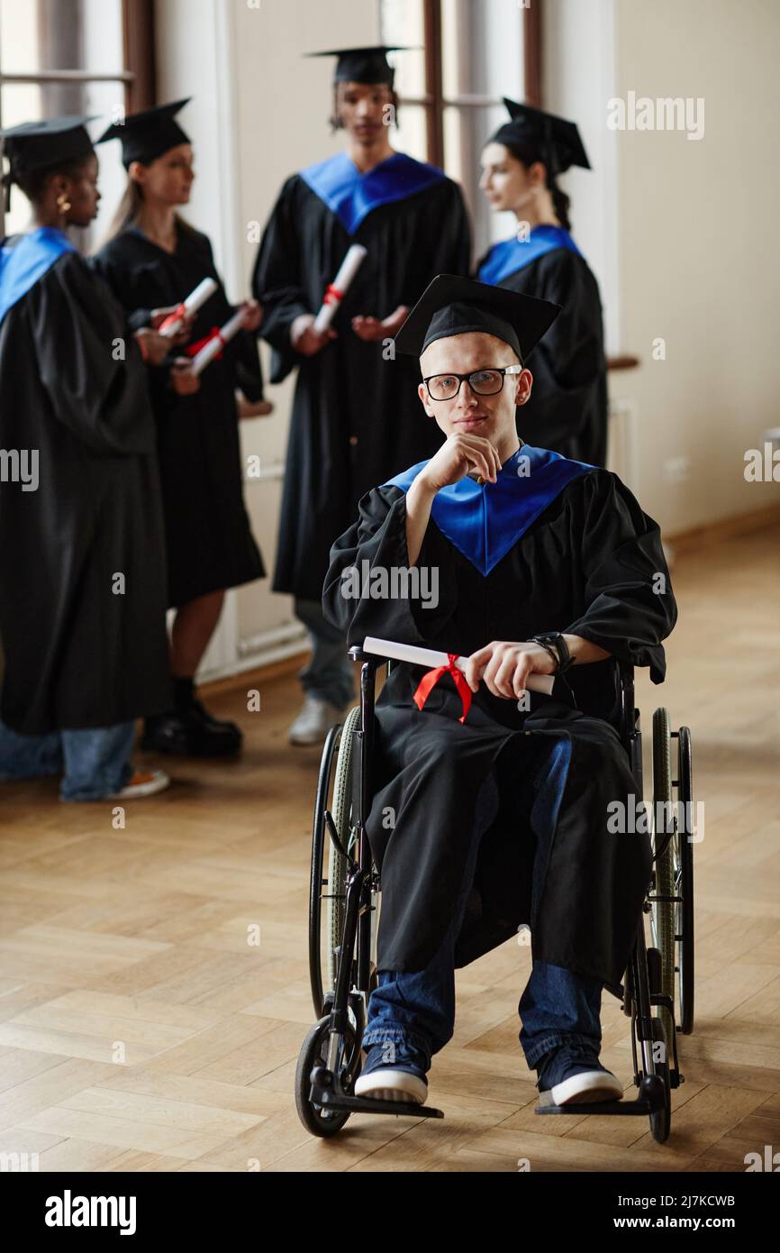 Full length portrait of young man with disability at graduation ...