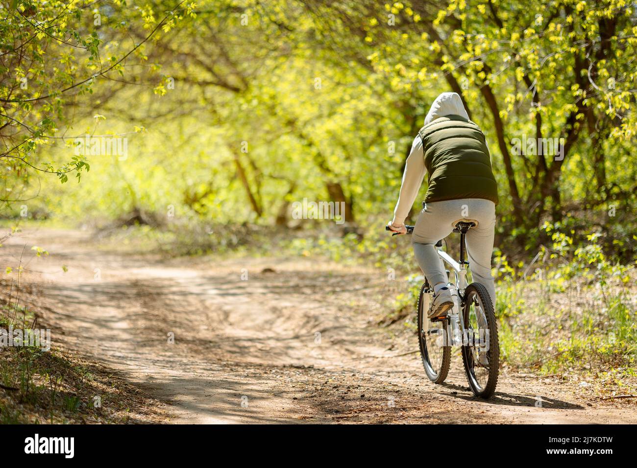 Man on bicycle rides through spring blooming park on sunny day. High ...